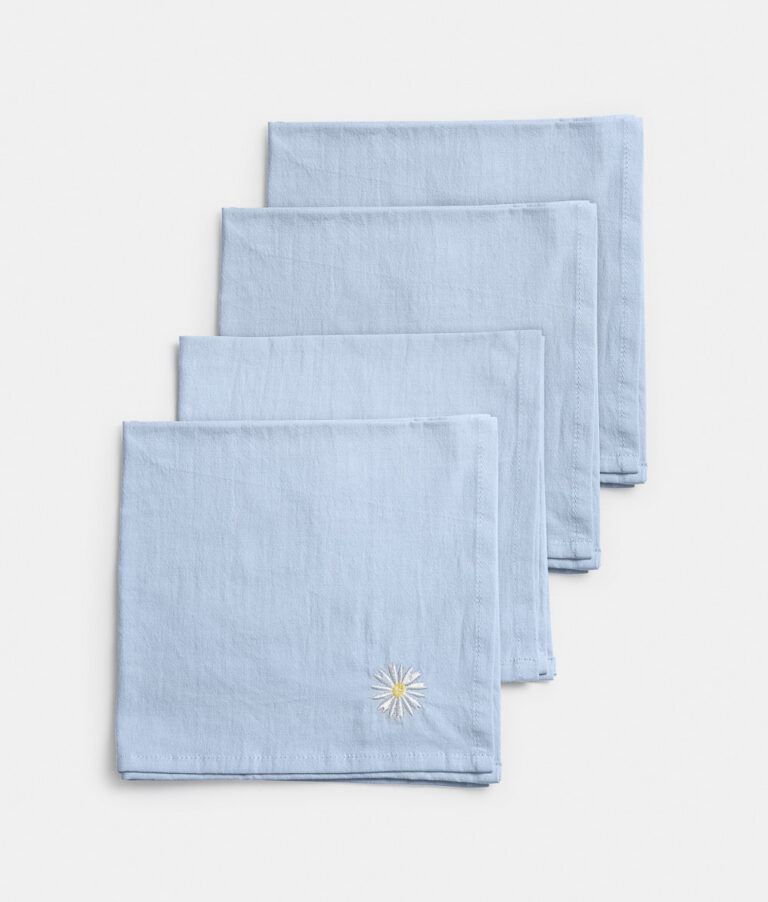 Hellblaue Serviette mit Gänseblümchen-Stickerei.
