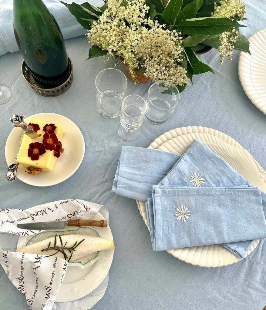 Hellblaue Serviette mit Gänseblümchen-Stickerei.